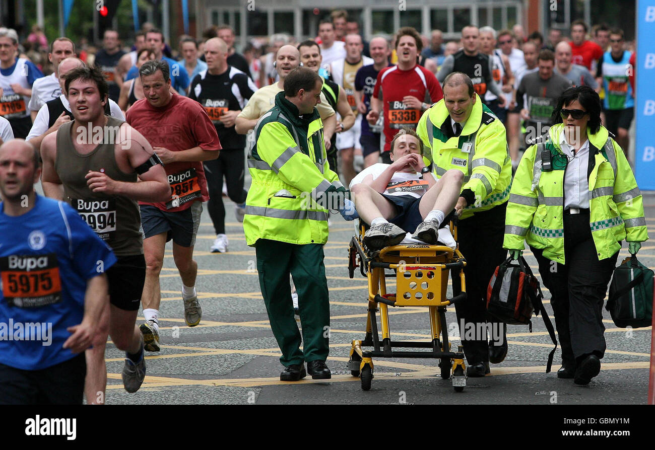 A runner is helped to the finishing line by medical staff in the ...