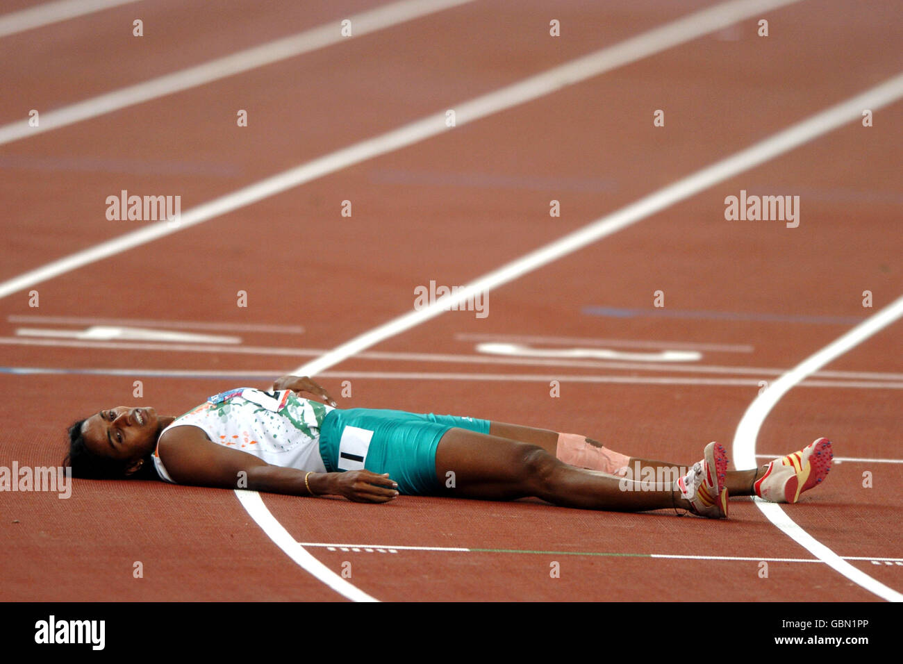 India's Soma Biswas lies exhausted on the track after her race Stock ...
