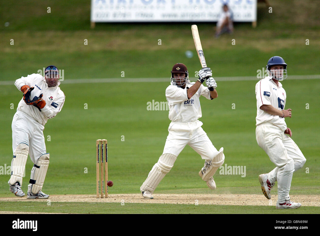 Surrey's Mark Ramprakash hits a boundary as Lancashire's Ian Sutcliffe ...