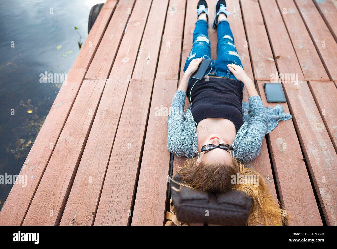 Young woman relaxing on pier Stock Photo - Alamy