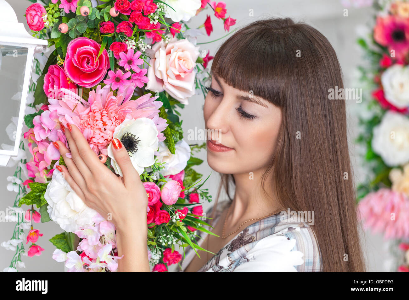 Beautiful brunette girl looking at the flowers. Spring Stock Photo - Alamy