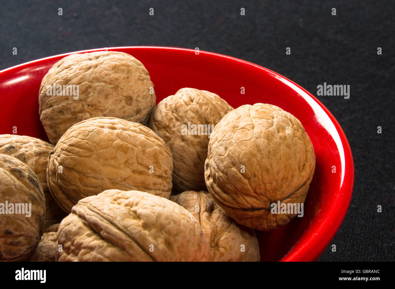 walnuts in red plate on black background Stock Photo - Alamy