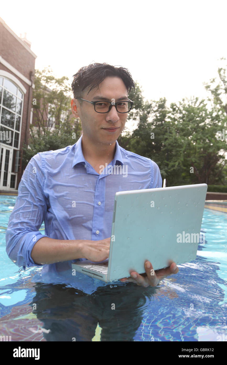 Young men use a computer in a swimming pool Stock Photo - Alamy