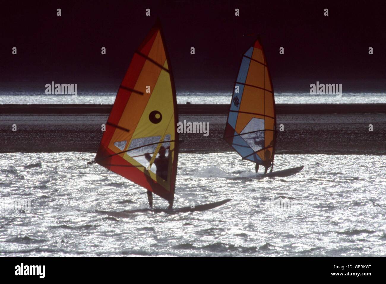 Two windsurfers sail into sunset at the marine lake hi-res stock ...