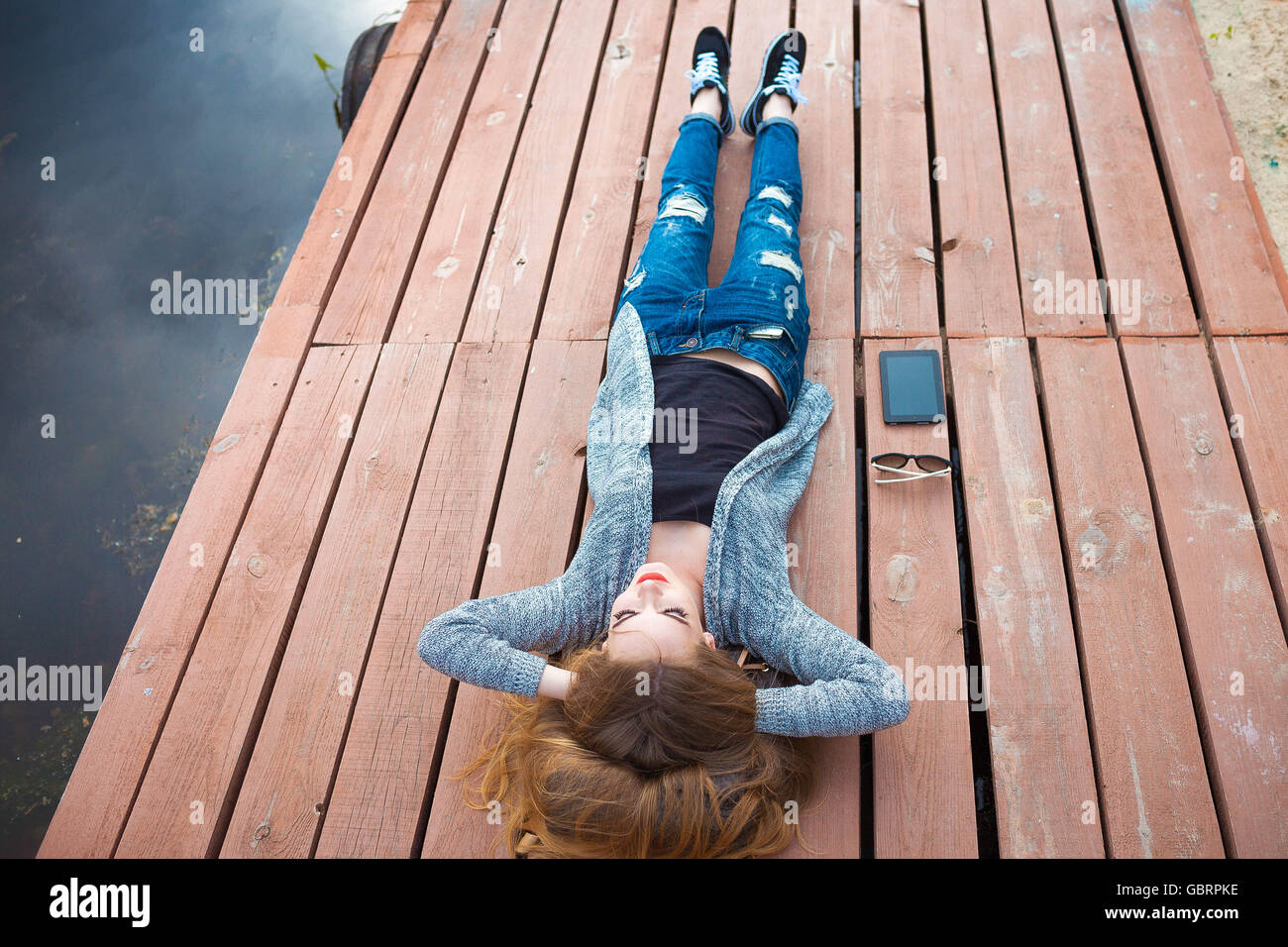 Young woman relaxing on pier Stock Photo - Alamy
