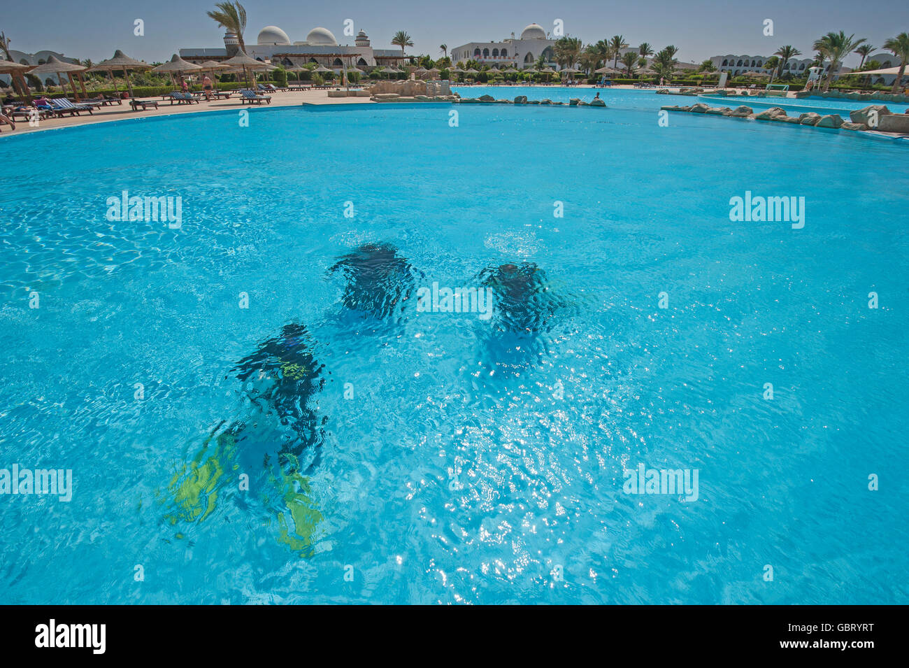 Three scuba divers training underwater in luxury tropical hotel resort ...