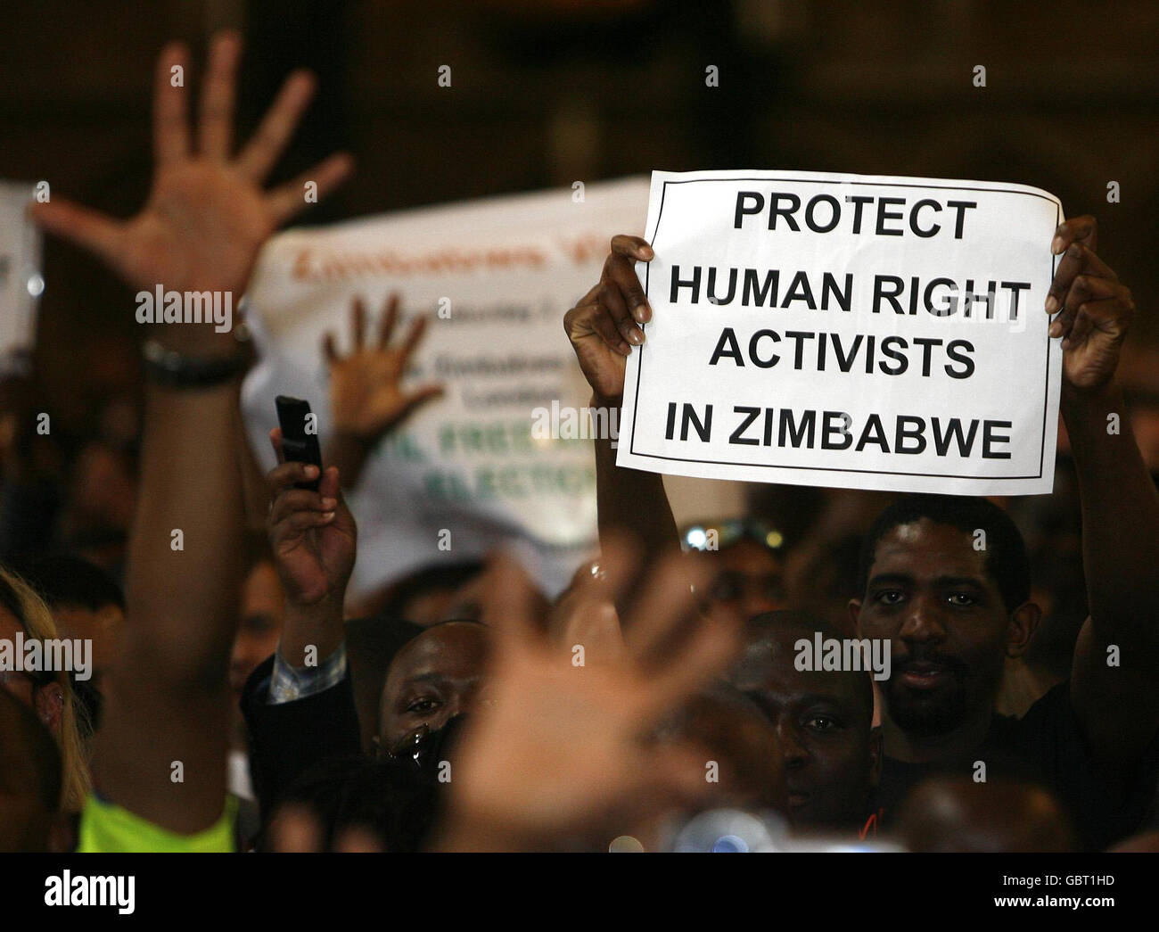 A man holds a poster accusing human rights record in Zimbabwe as ...
