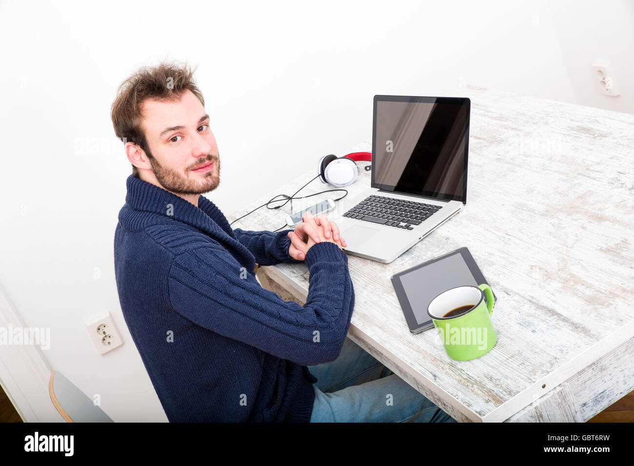 A young man working online from home with his laptop computer and ...