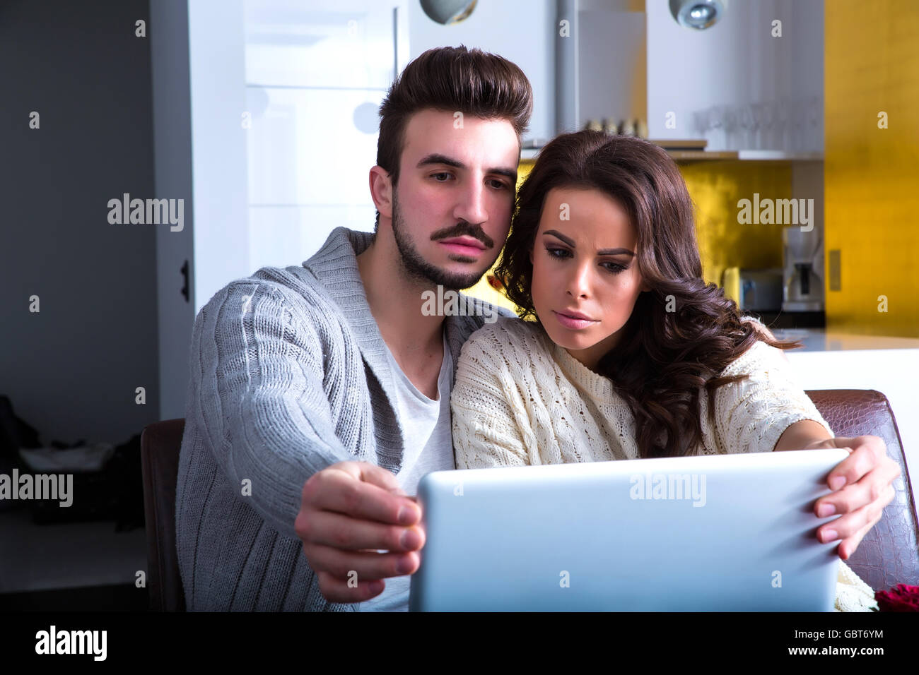 A young couple using in the evening their laptop computers at home and ...