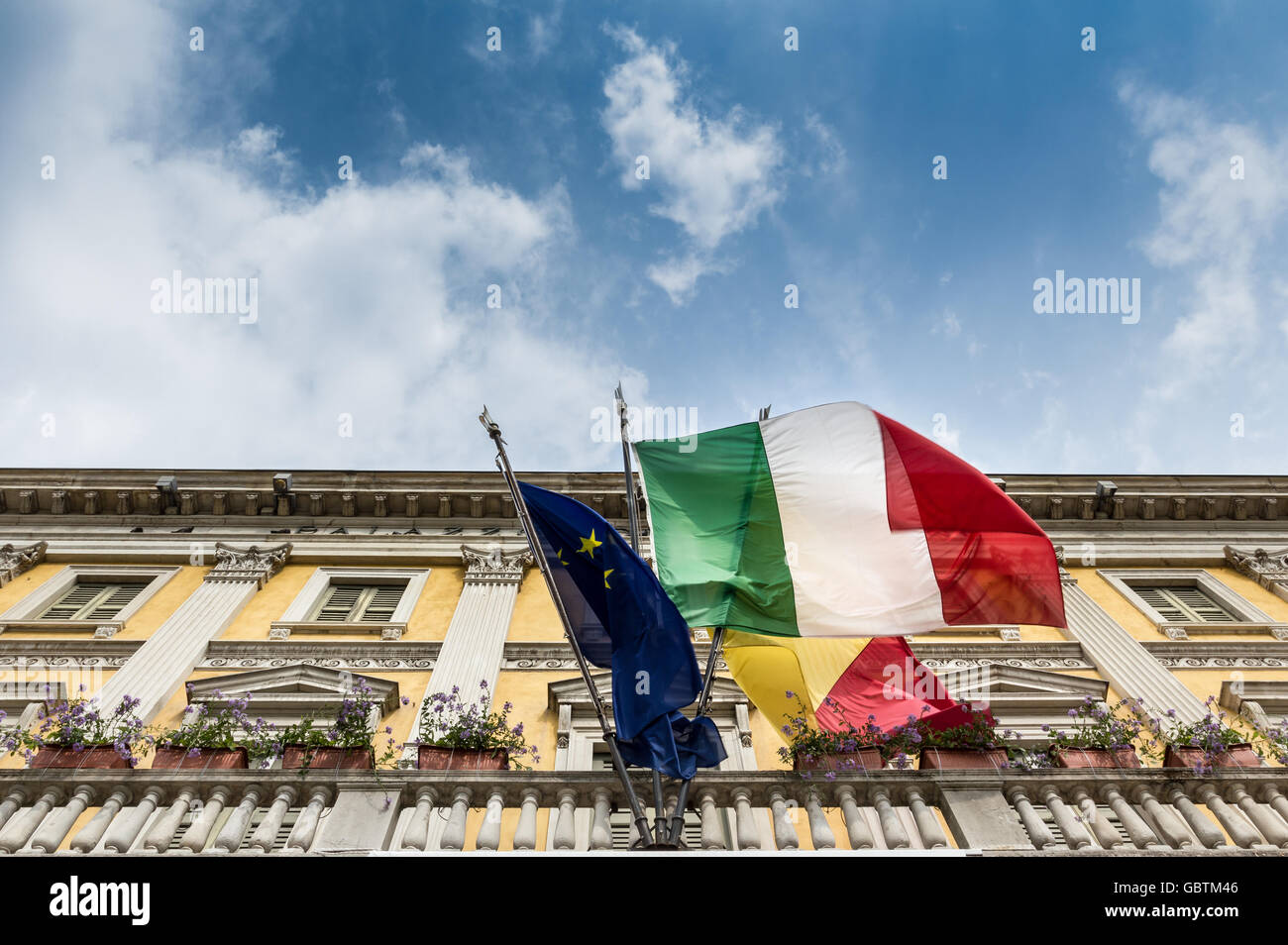 Facade of an ancient building with Italian and European flag, against a ...