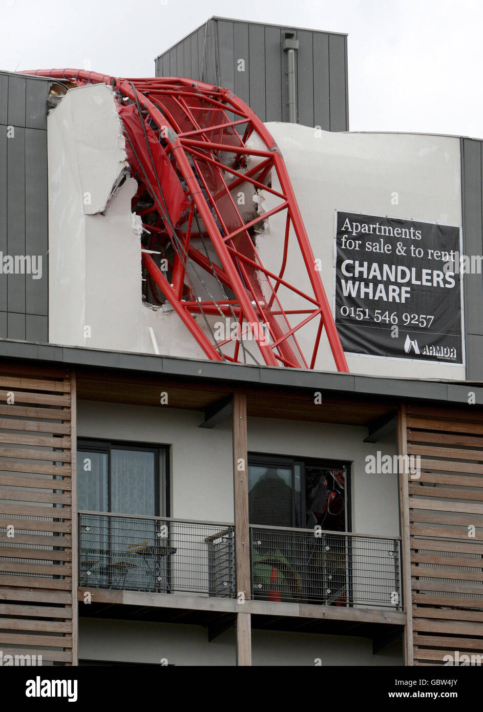 A tower crane lies across the top of residential apartments after ...