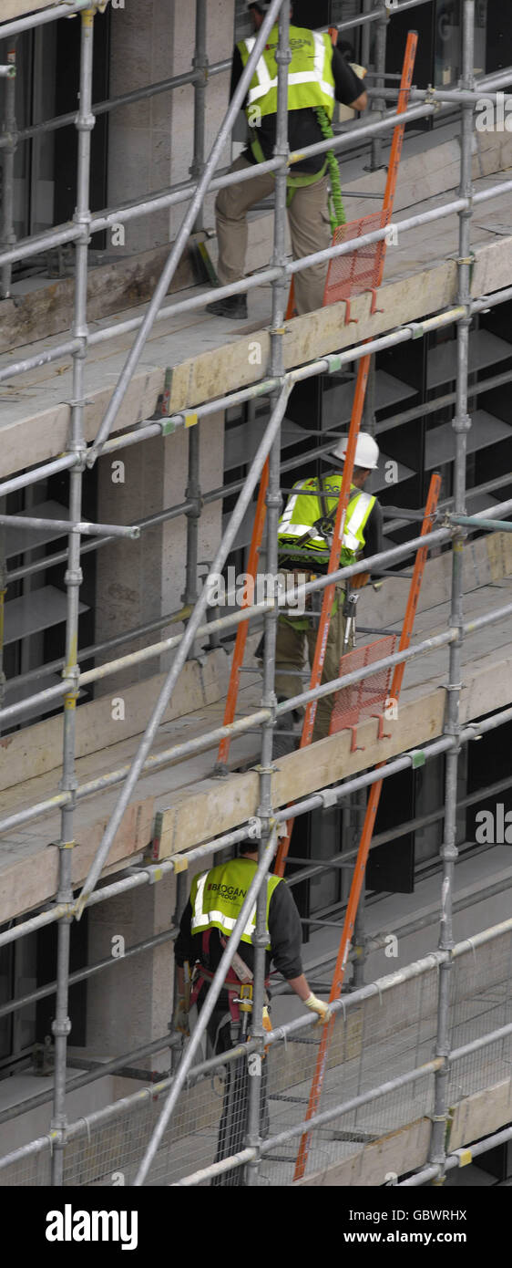 Workers climb ladders on scaffolding on the outside of a newly built ...