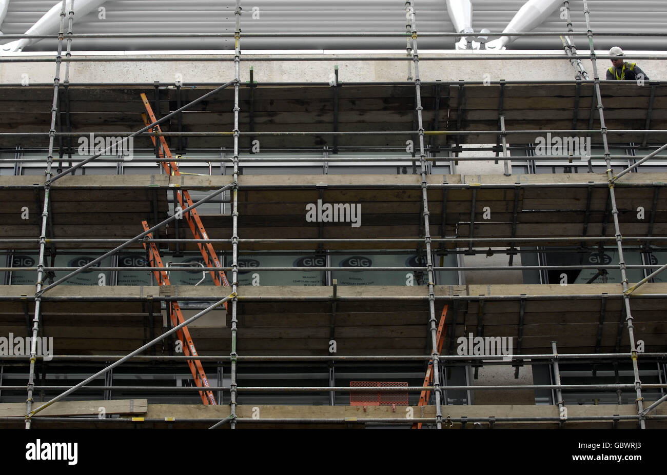 A worker removes scaffolding from the outside of a newly built office ...
