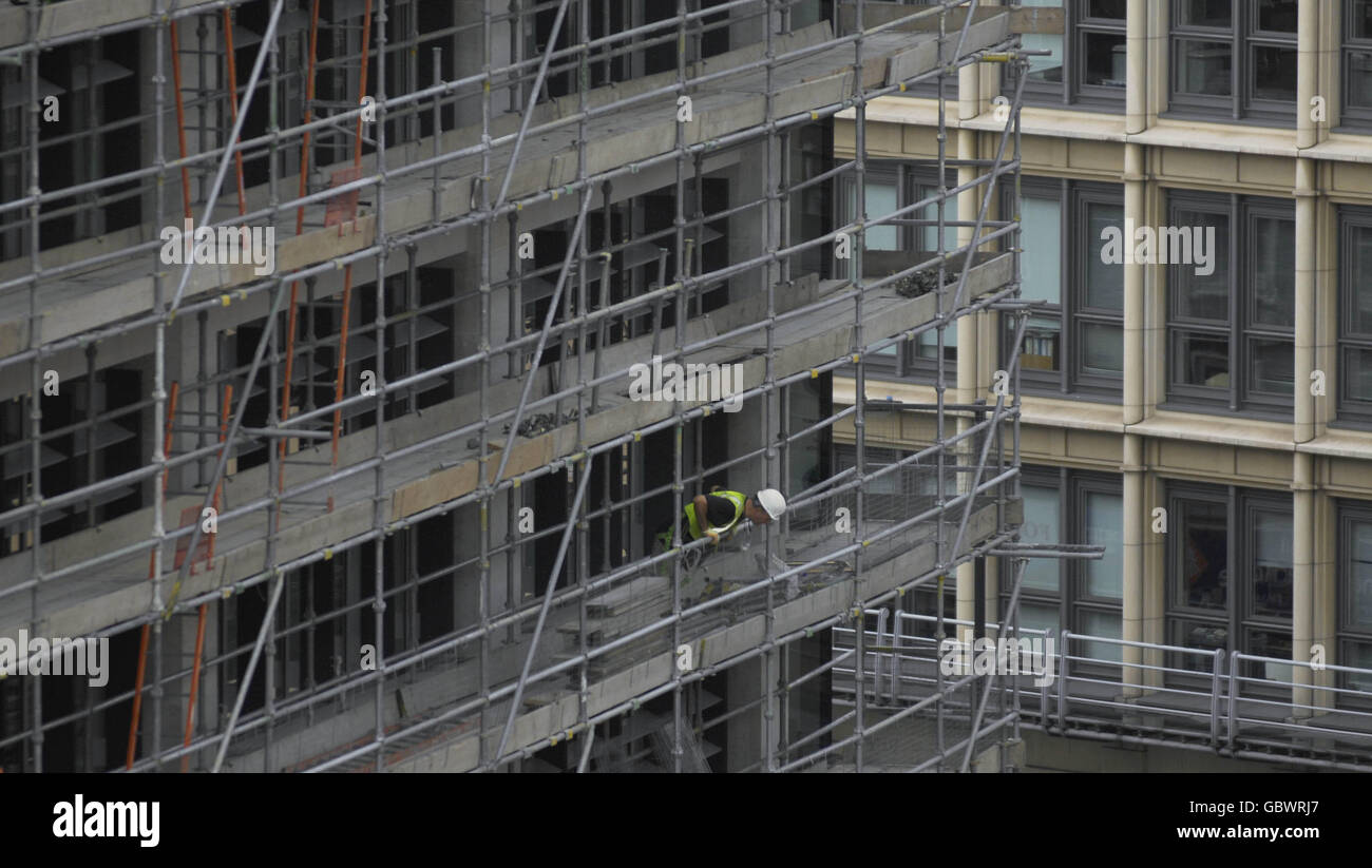 A worker looks over the side of scaffolding on the outside of a newly ...