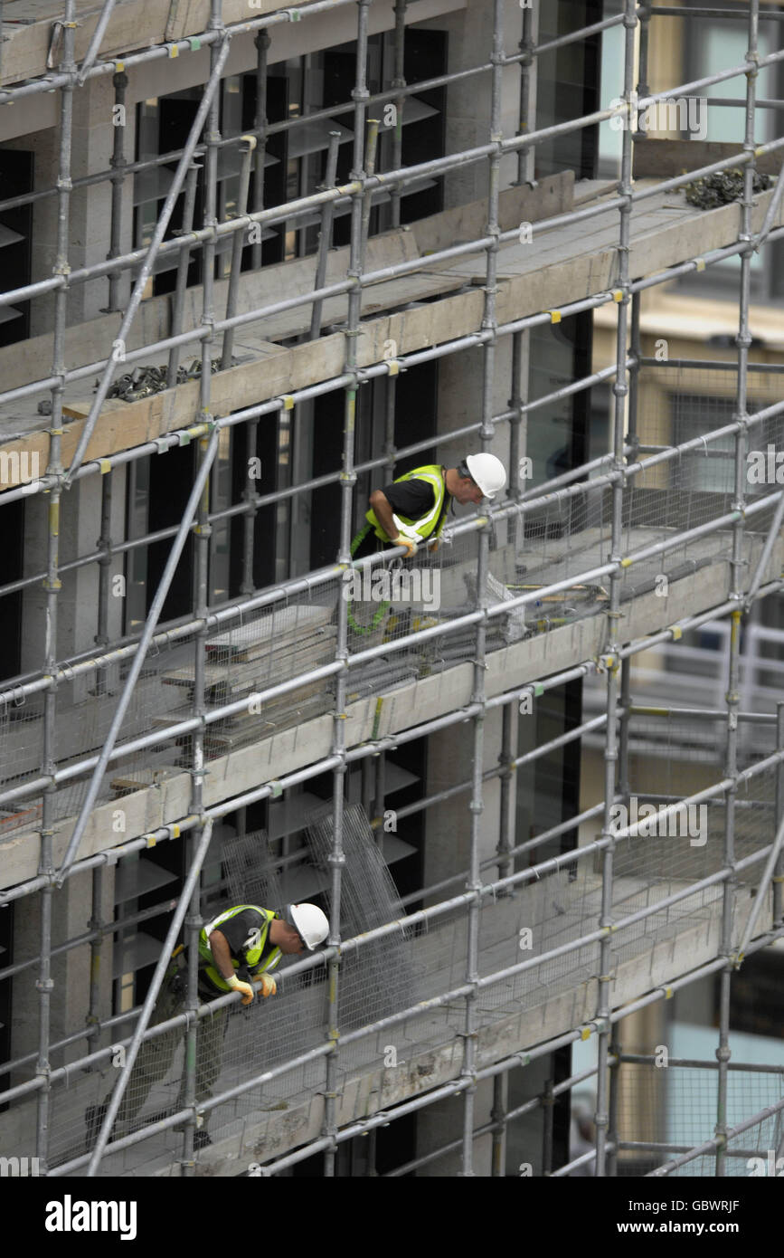 Two workers look over the side of scaffolding on the outside of a newly ...