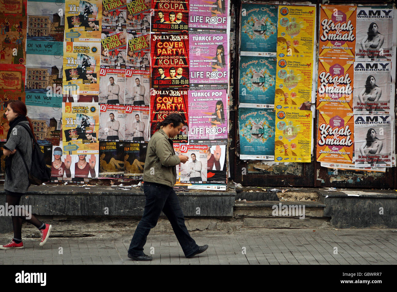 A woman walks past a wall covered in advertisment posters in Istanbul ...