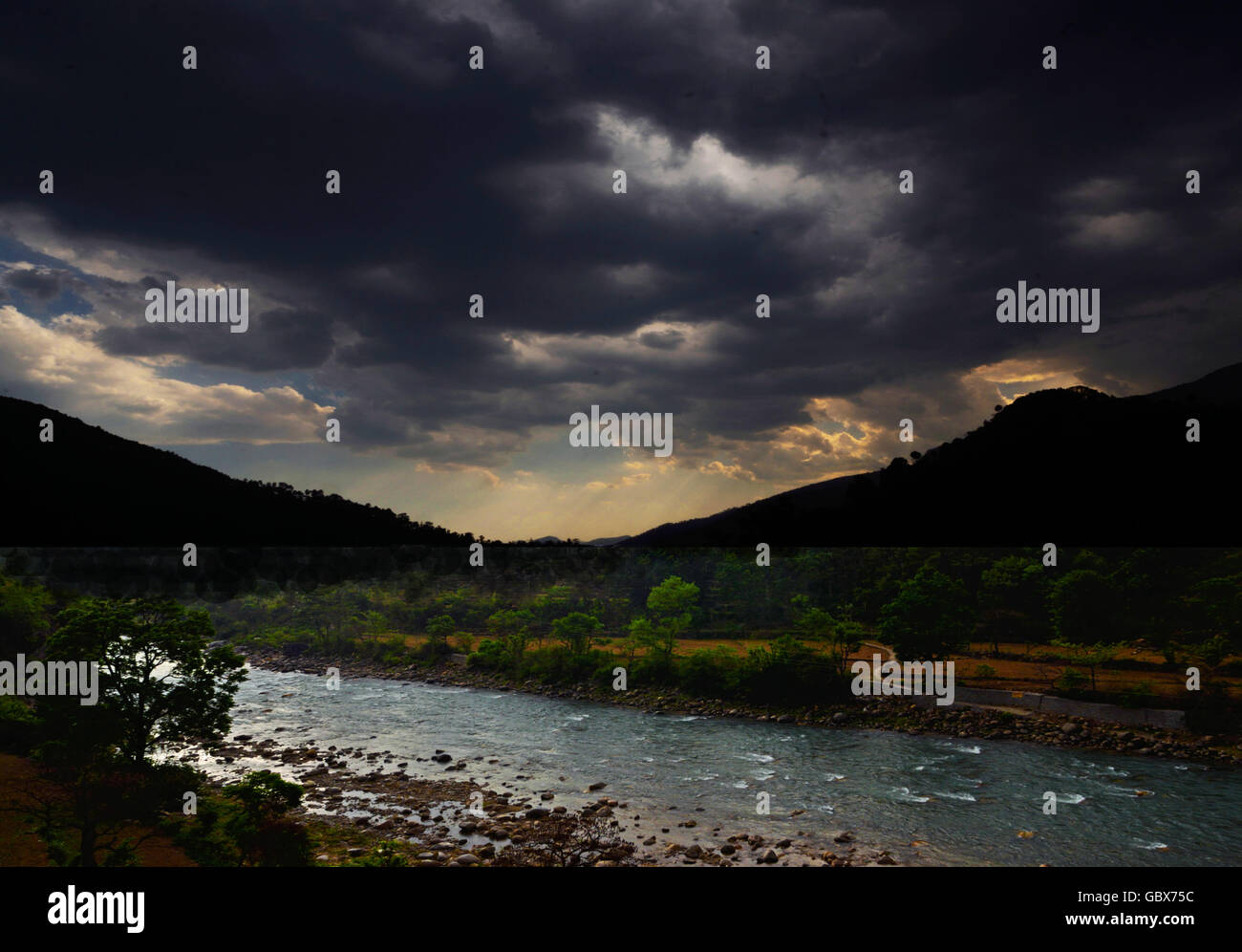 Mandakini river flows gently through a valley as dark rain clouds ...