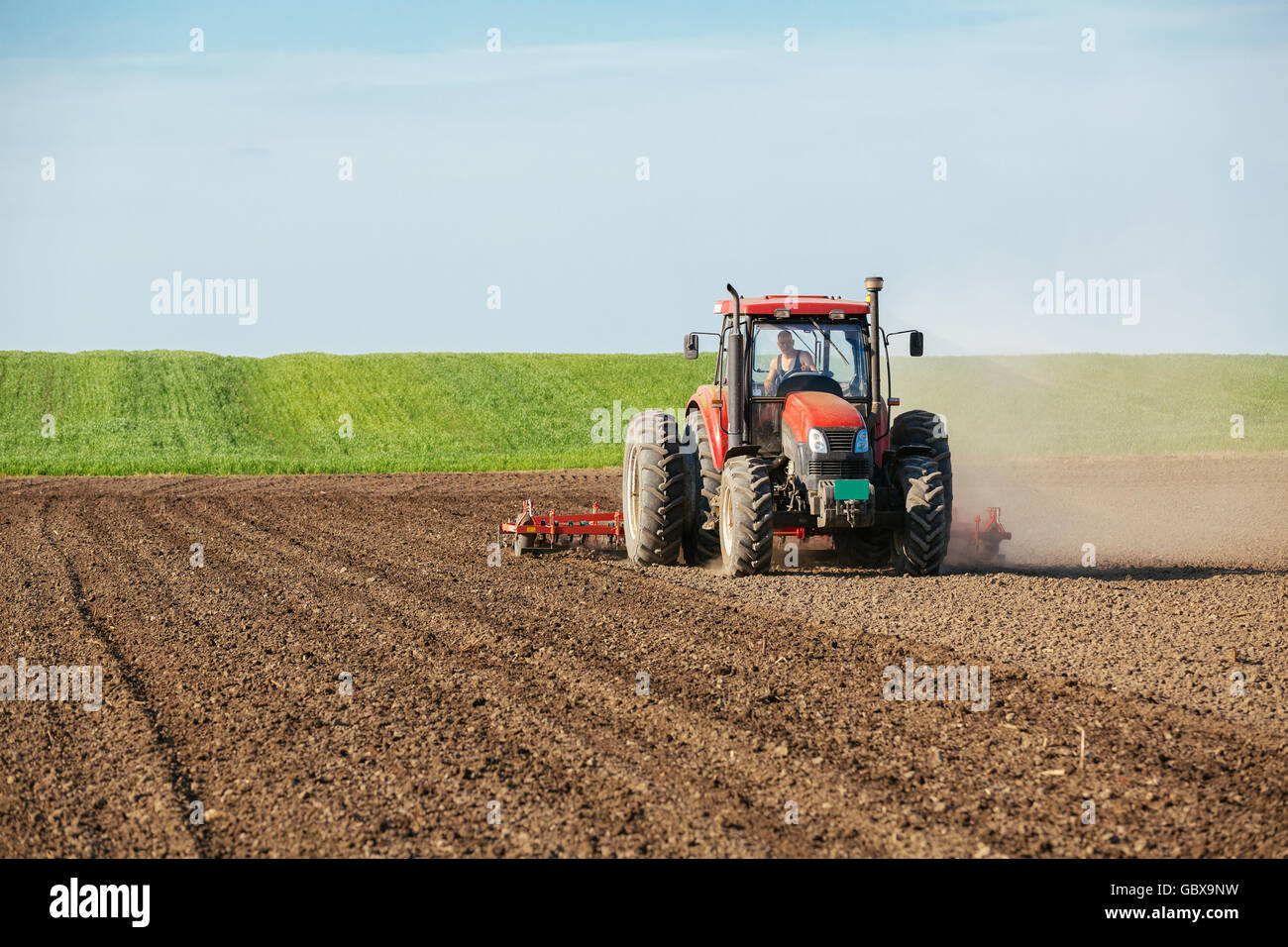 Tractor cultivating field at spring Stock Photo - Alamy