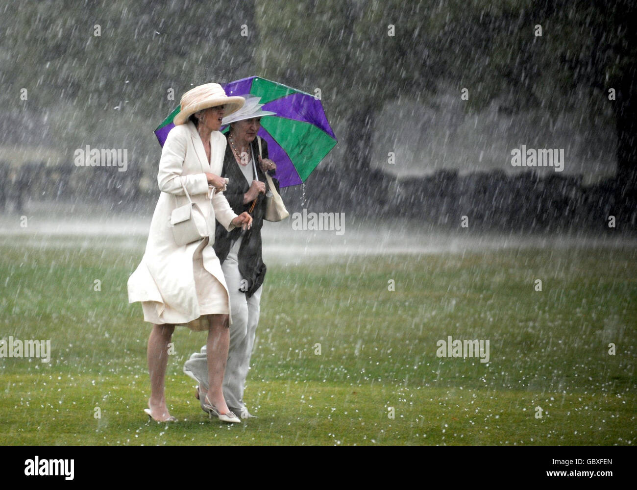 Guests head for cover as heavy rain begins to fall during the first ...