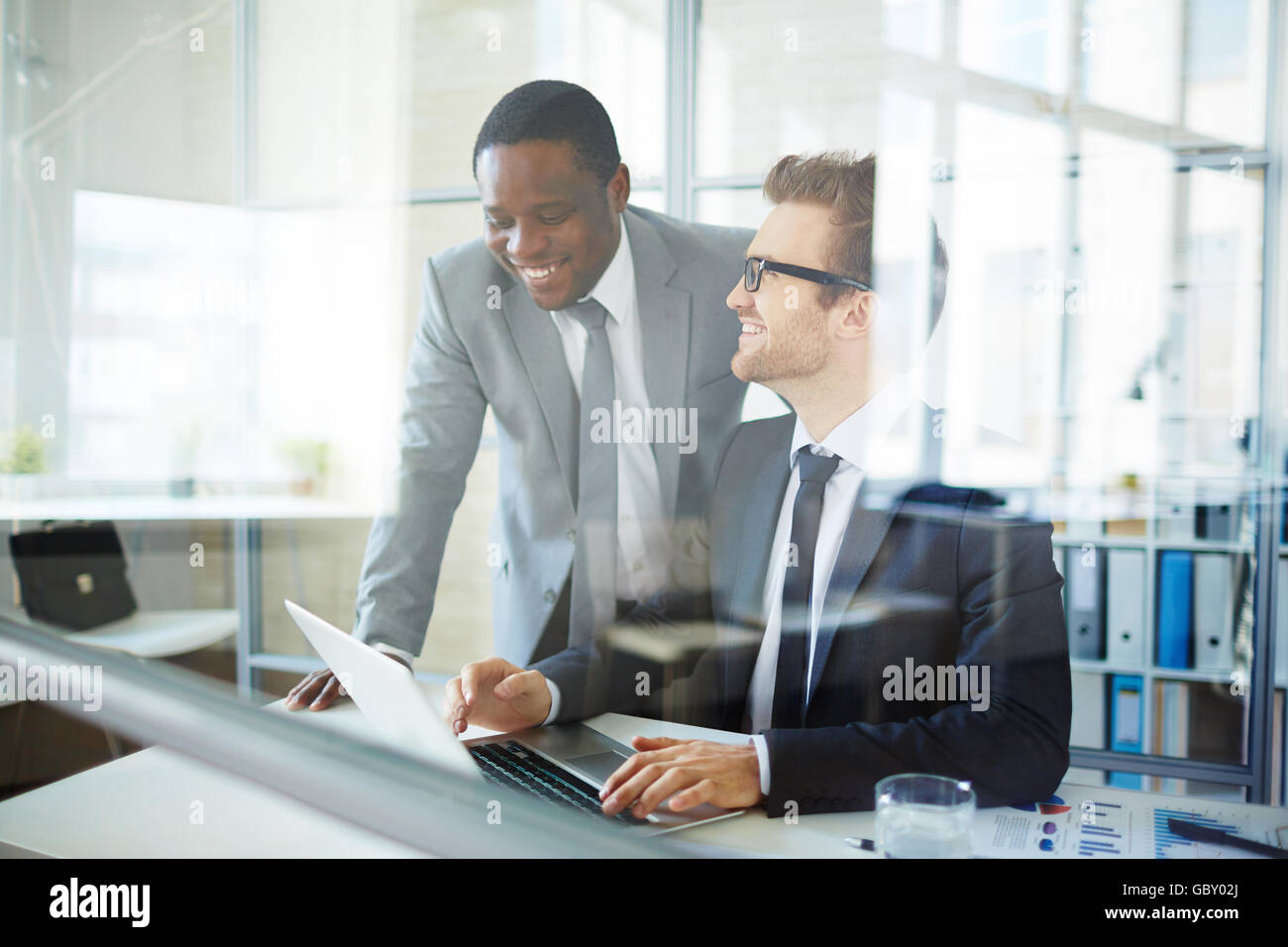 Two colleagues using computer together at office Stock Photo - Alamy