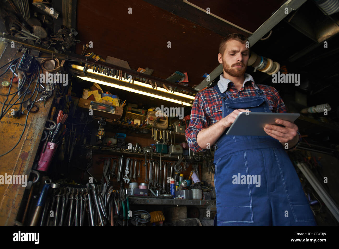 Manual worker using touchpad in workshop Stock Photo - Alamy