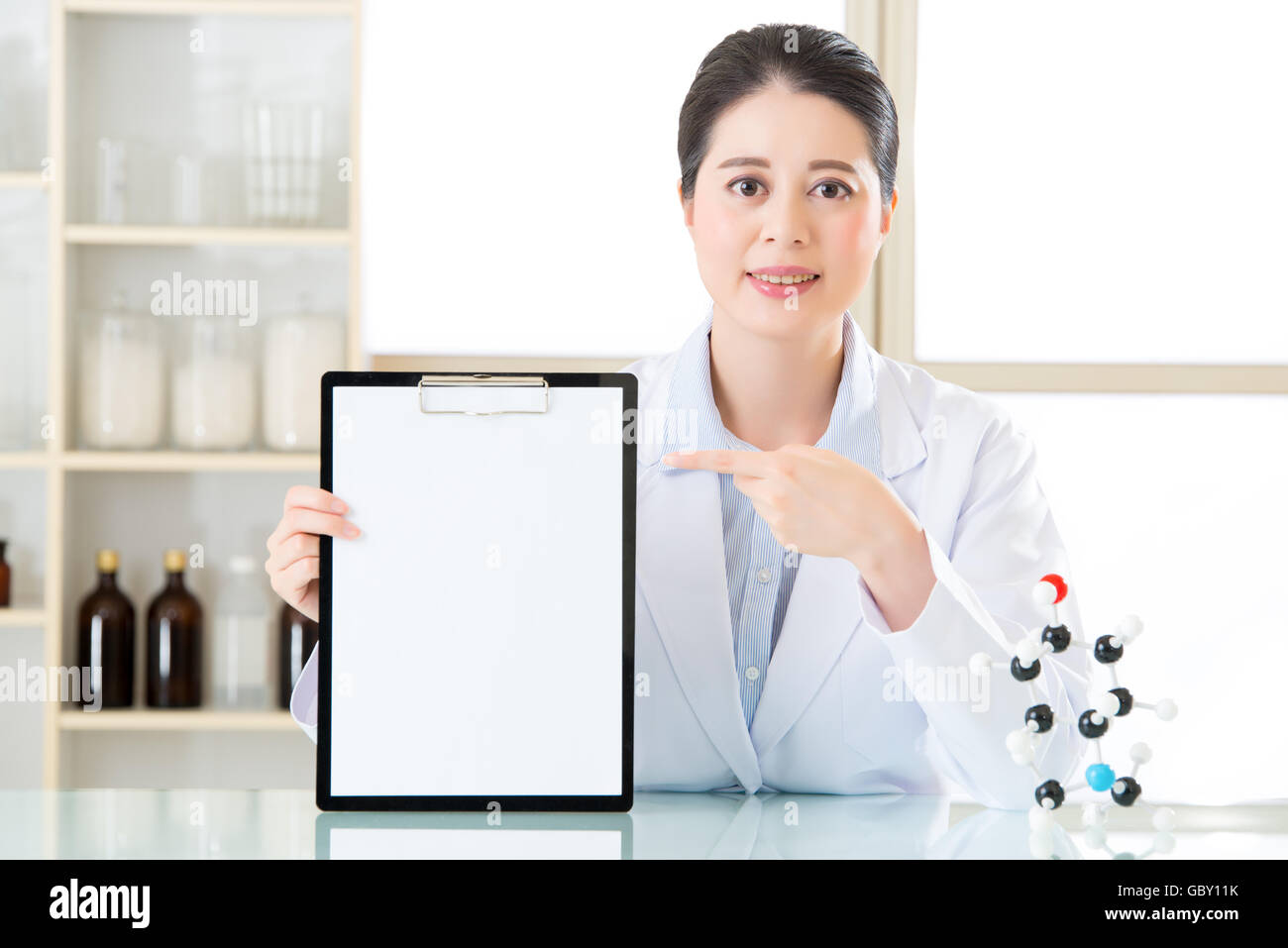 Happy asian female scientist holding clipboard and point it with ...