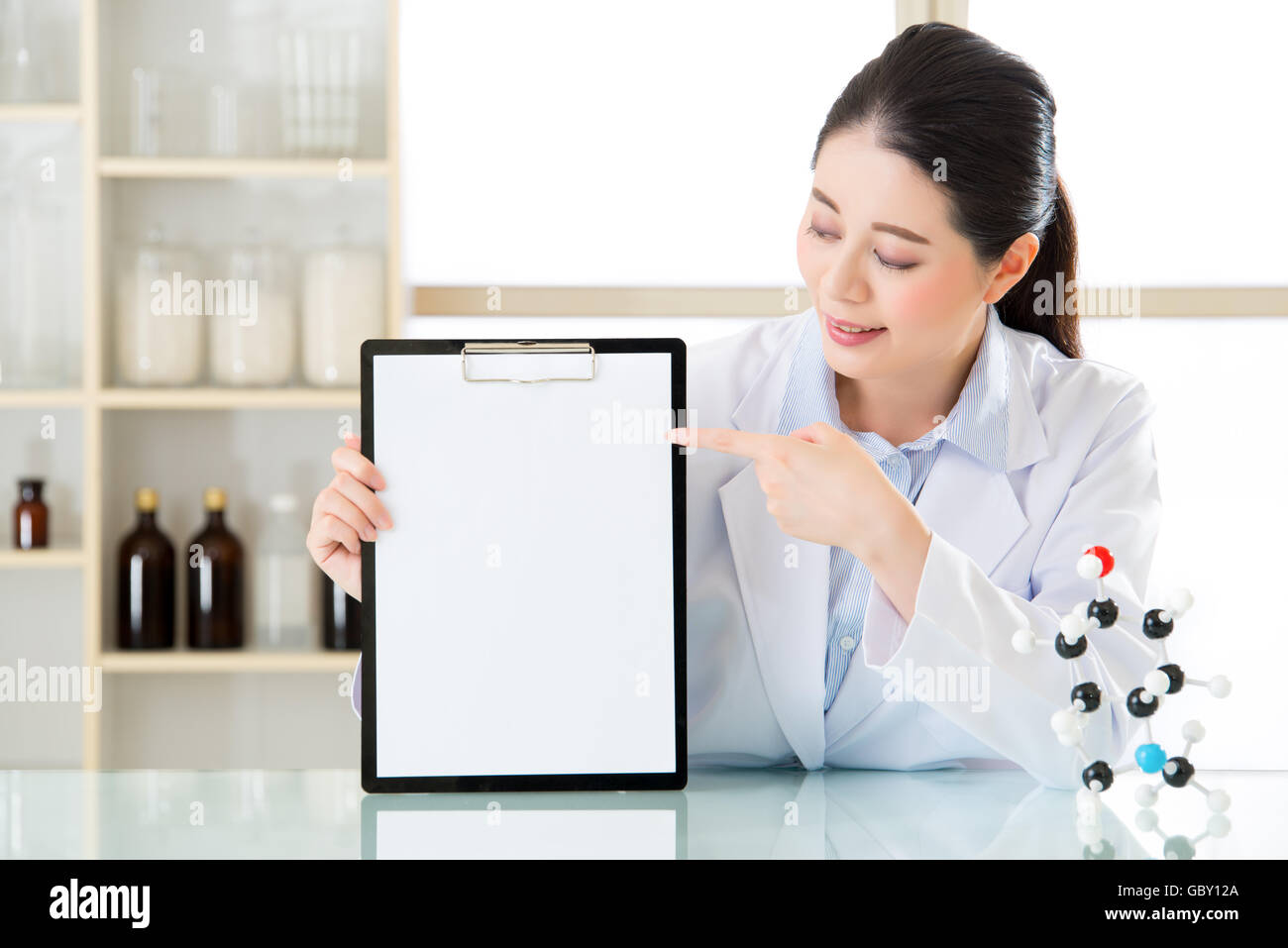 Happy asian female scientist holding clipboard and point it with ...