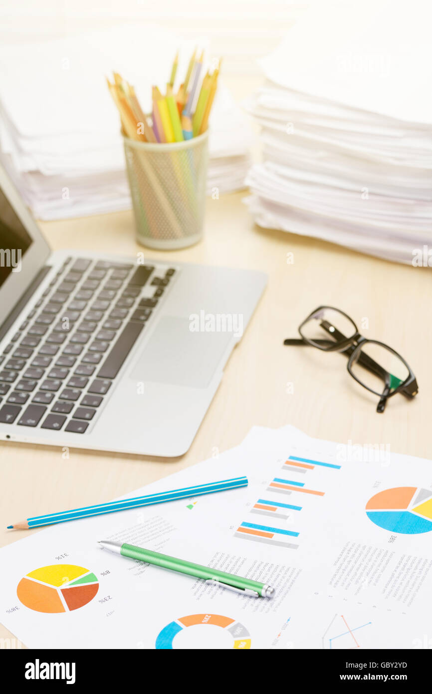 Office workplace with laptop, reports and pencils on wooden desk table ...