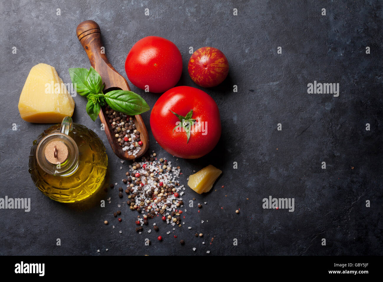 Fresh ripe garden tomatoes and spices on stone table. Top view with ...