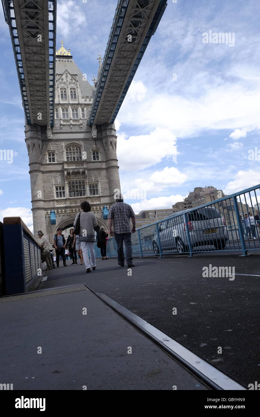 Tourists walk under the overhead walkway at Tower Bridge City of London ...