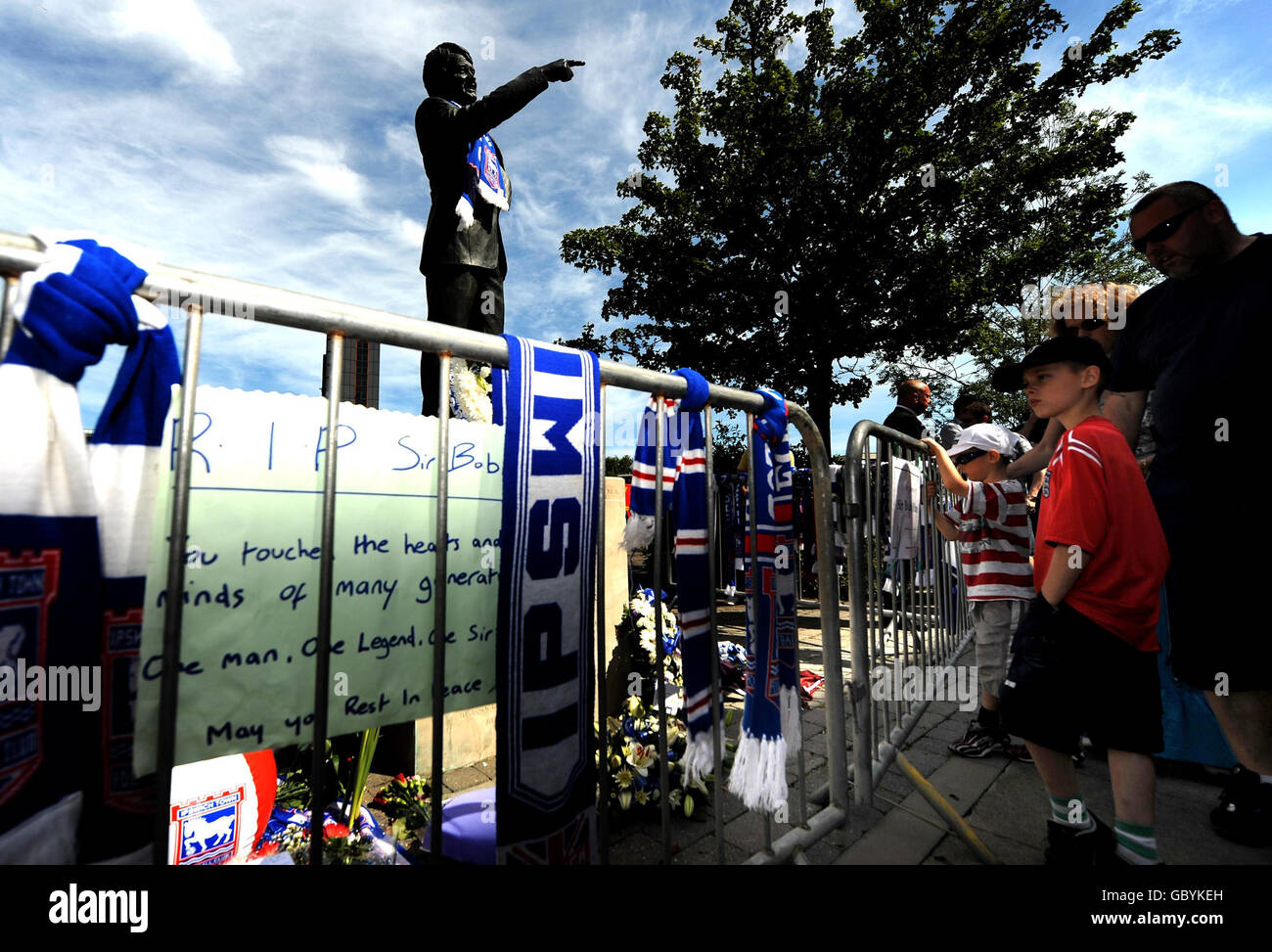 Two boys look on as tributes are seen beside a statue of Bobby Robson ...