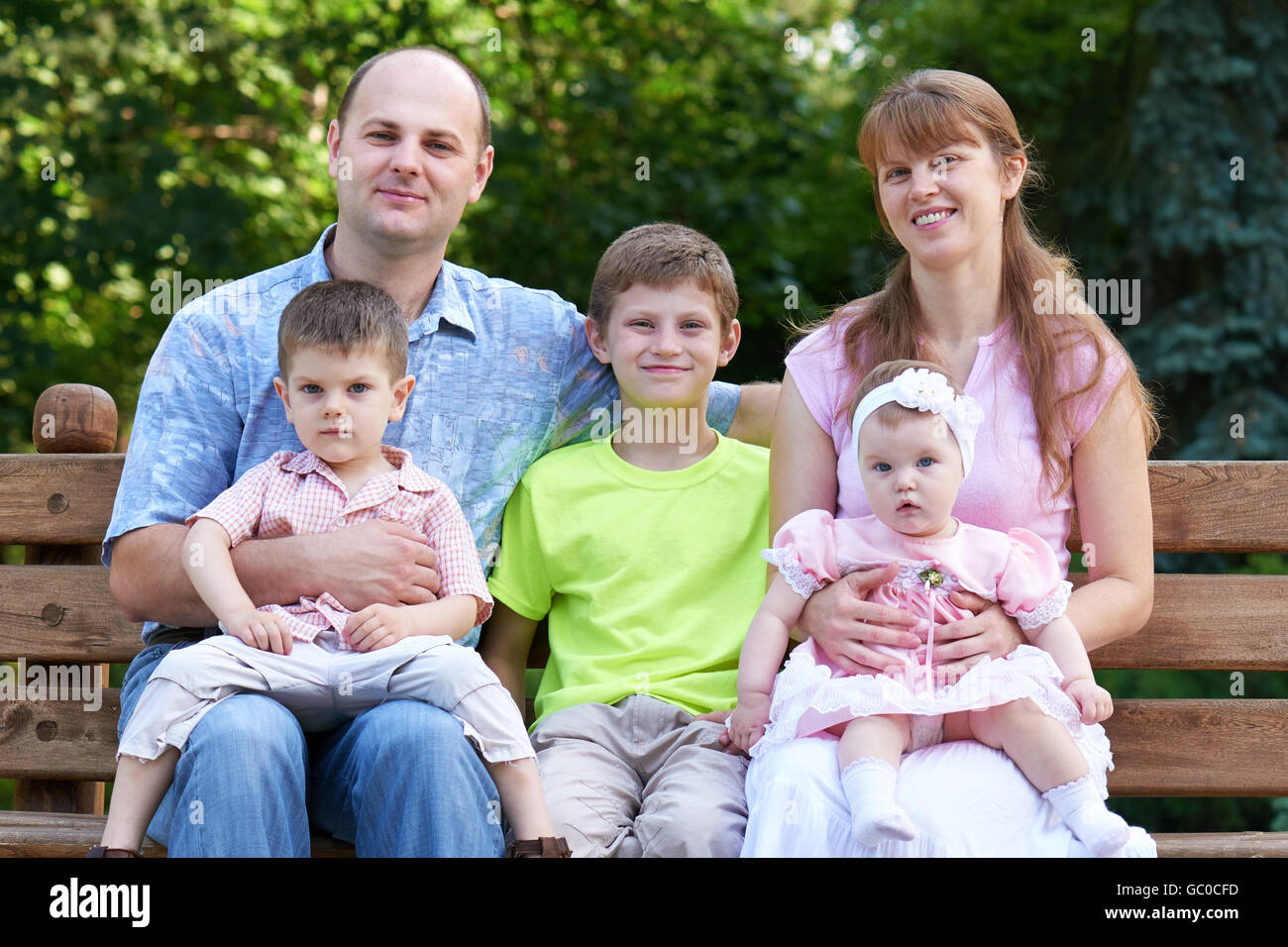 happy family portrait on outdoor, group of five people sit on wooden ...