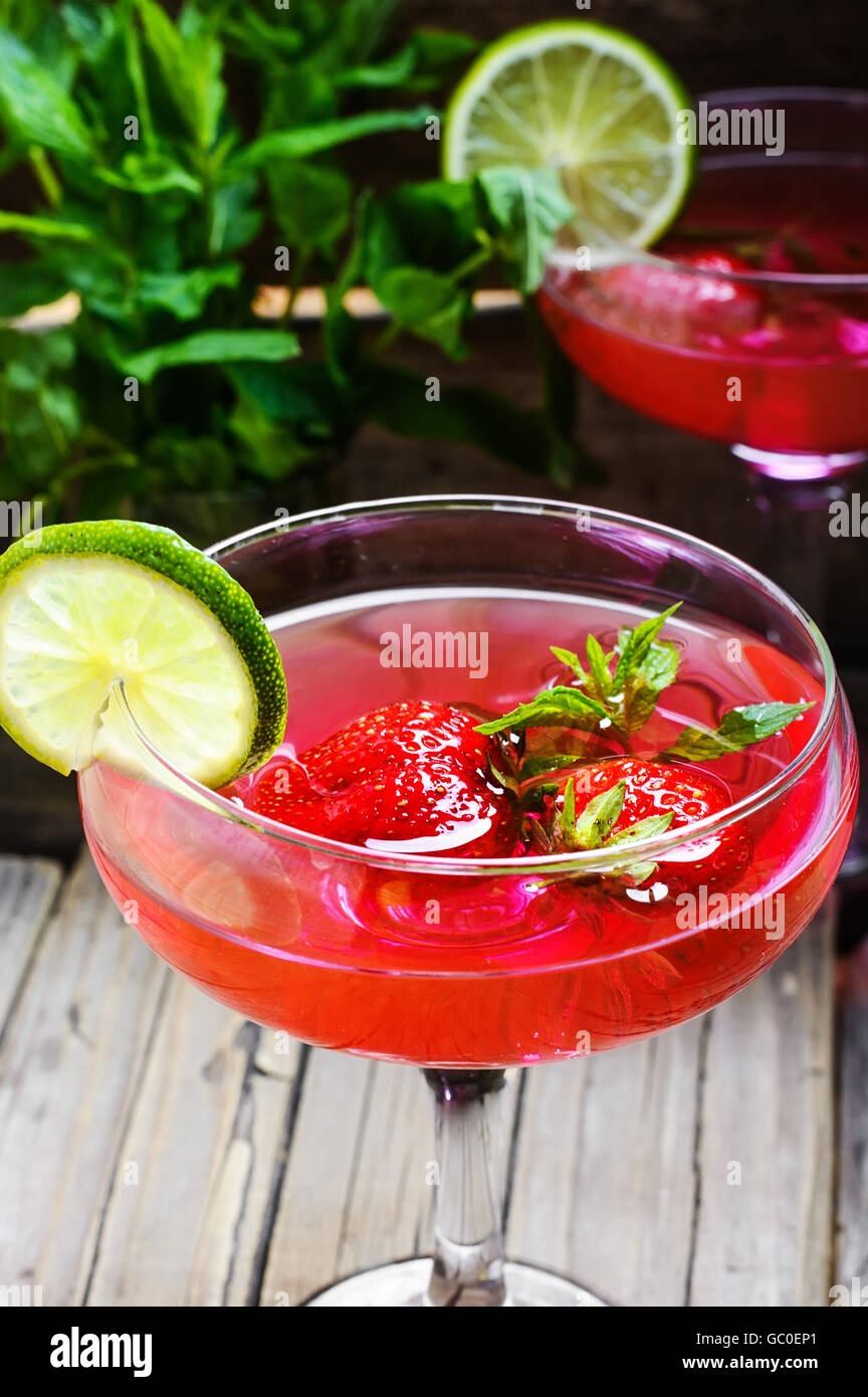 alcohol cocktail in glass on a long stalk with strawberries and lime ...