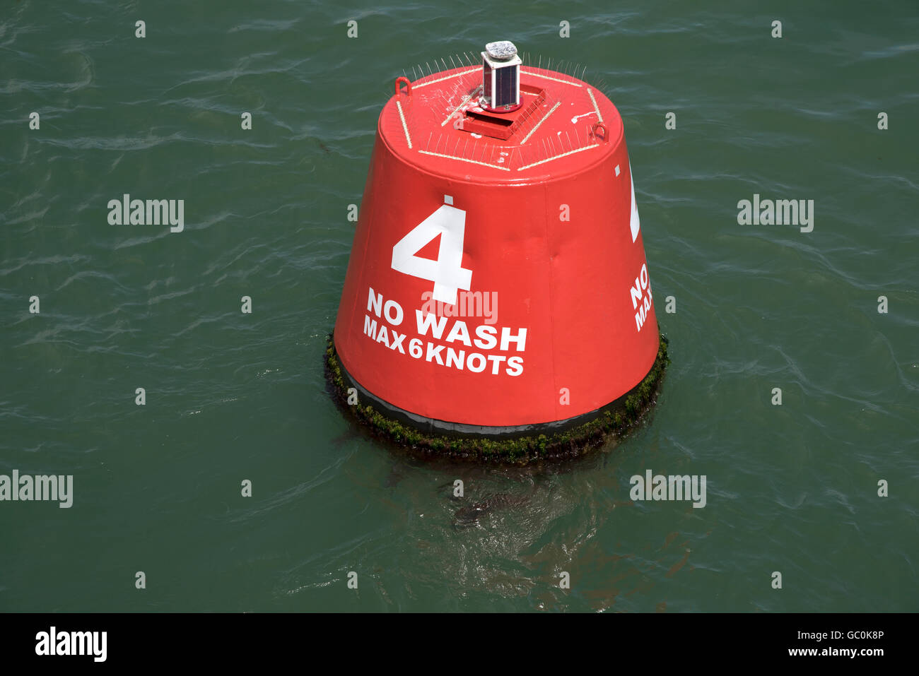 A red Marine buoy advising a maximum speed of 6 knots on the approach ...