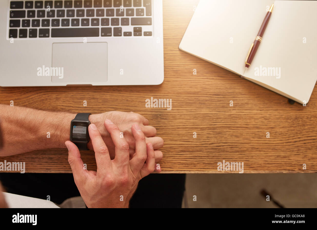 Top view shot of man sitting at his workplace checking time on his ...
