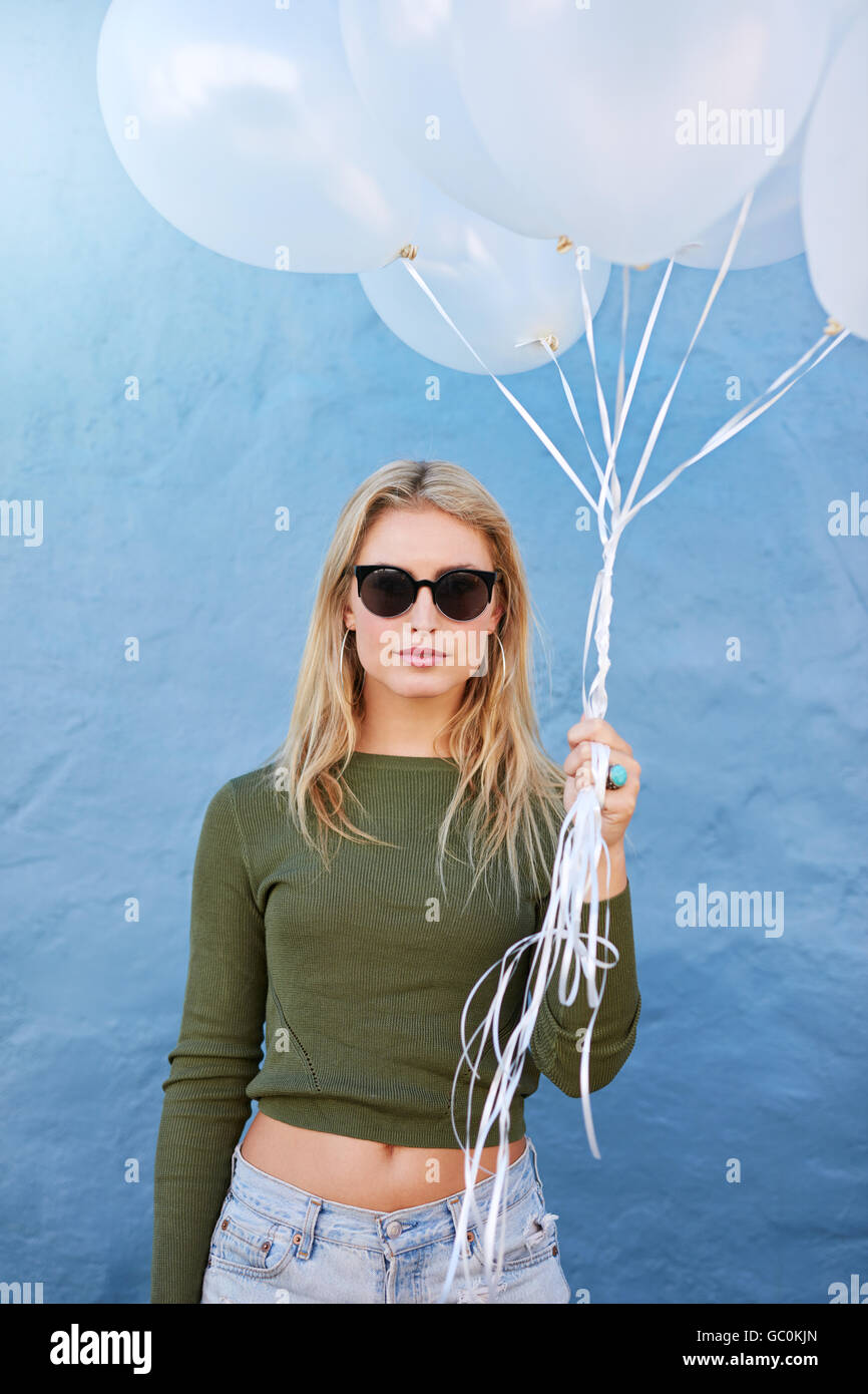 Pretty young woman with white balloons on blue background. Trendy young ...