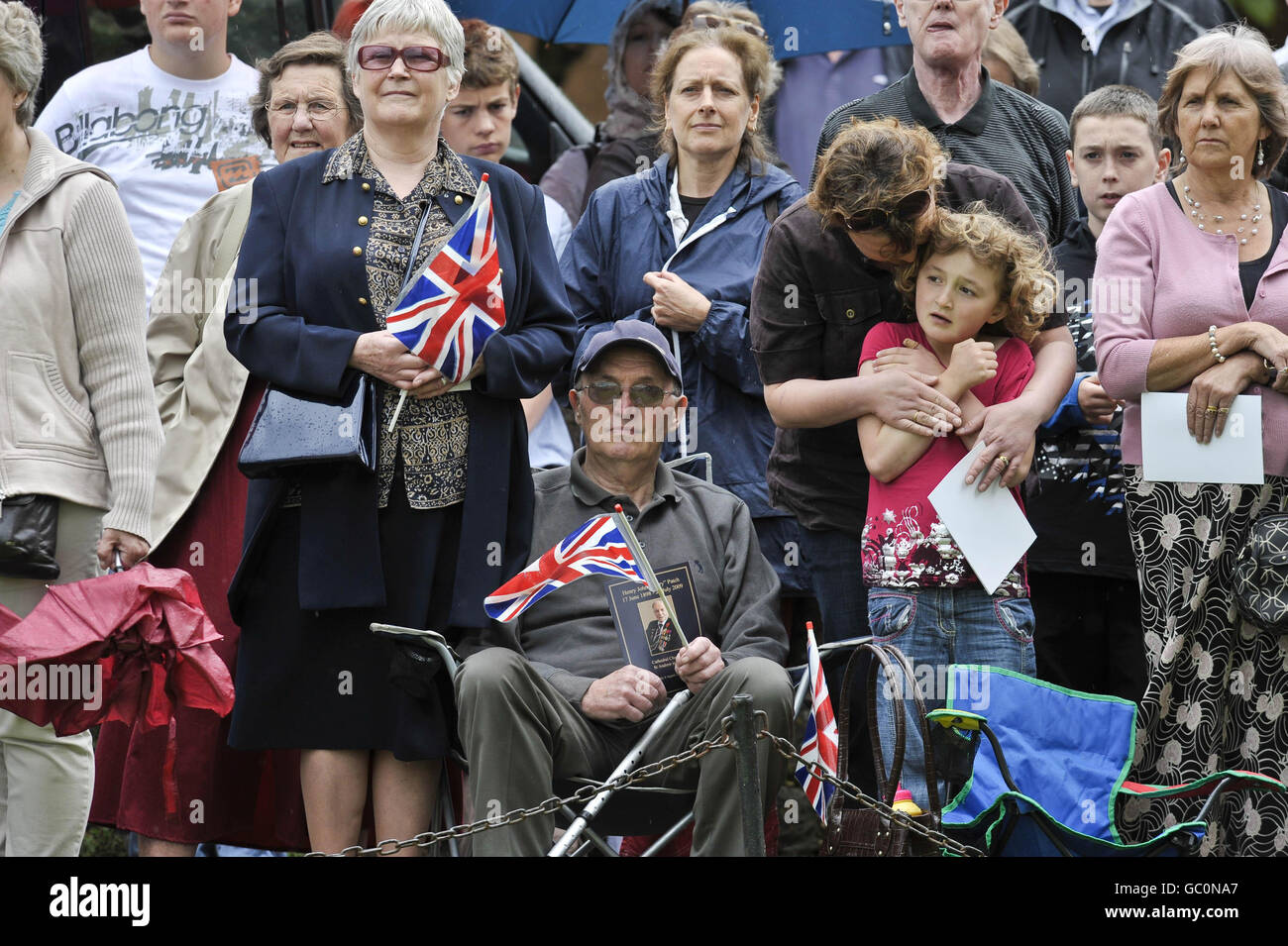 Some members of the crowd hold Union Jack flags as the coffin of Harry ...