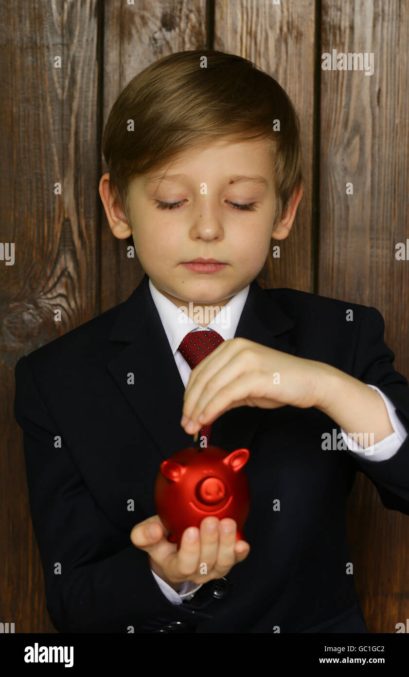 Boy in a suit with a red piggy bank - business concept Stock Photo - Alamy