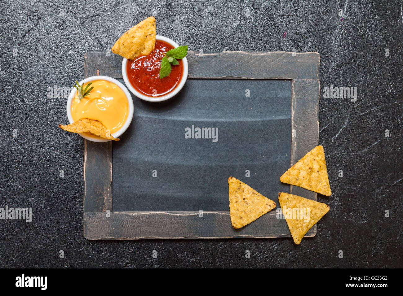 Mexican nacho with sauces and chalk board on black background, top view ...