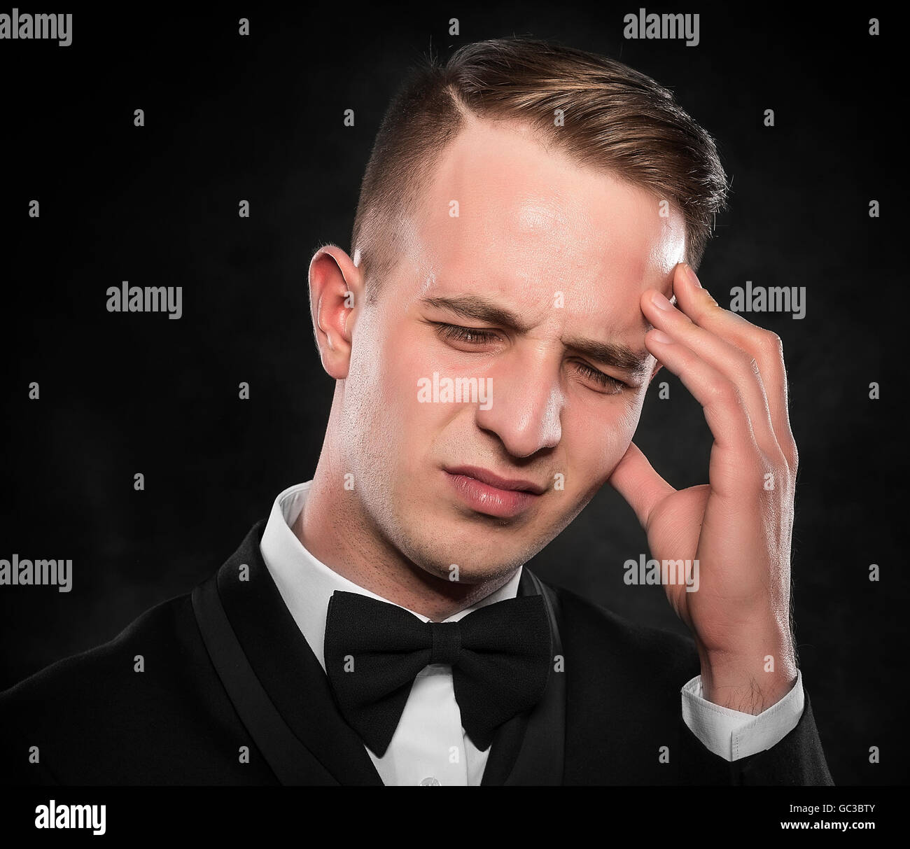 Young man holding his head feeling a headache or intensely thinking ...