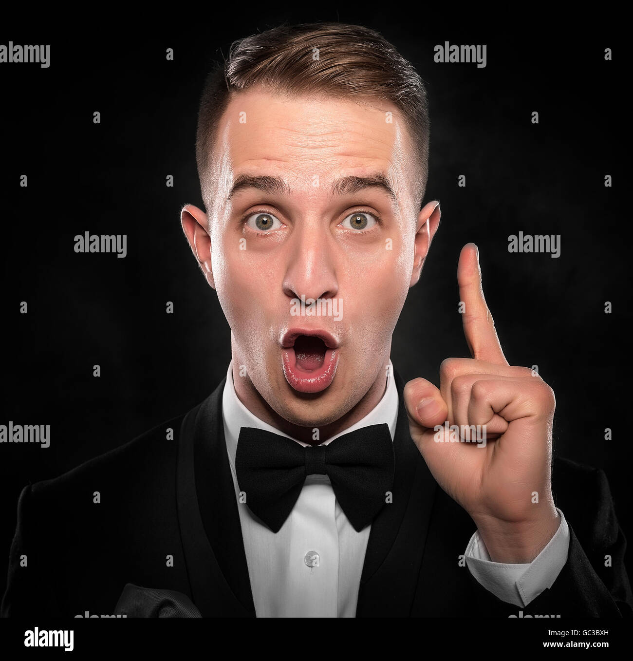Idea. Young man shows finger up over darck background Stock Photo - Alamy