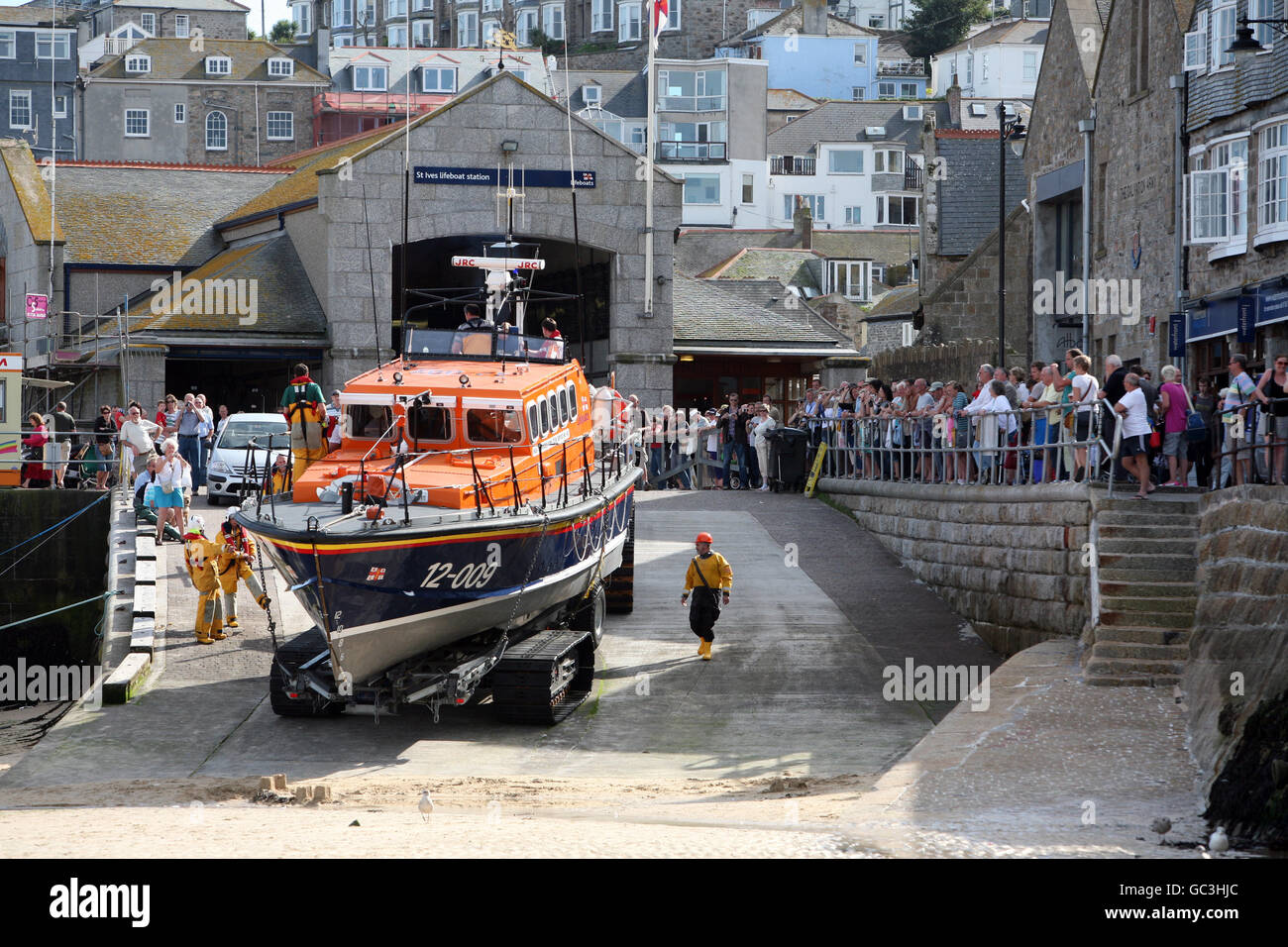 Spectators watch a tractor helping to launch the Mersey-class lifeboat ...
