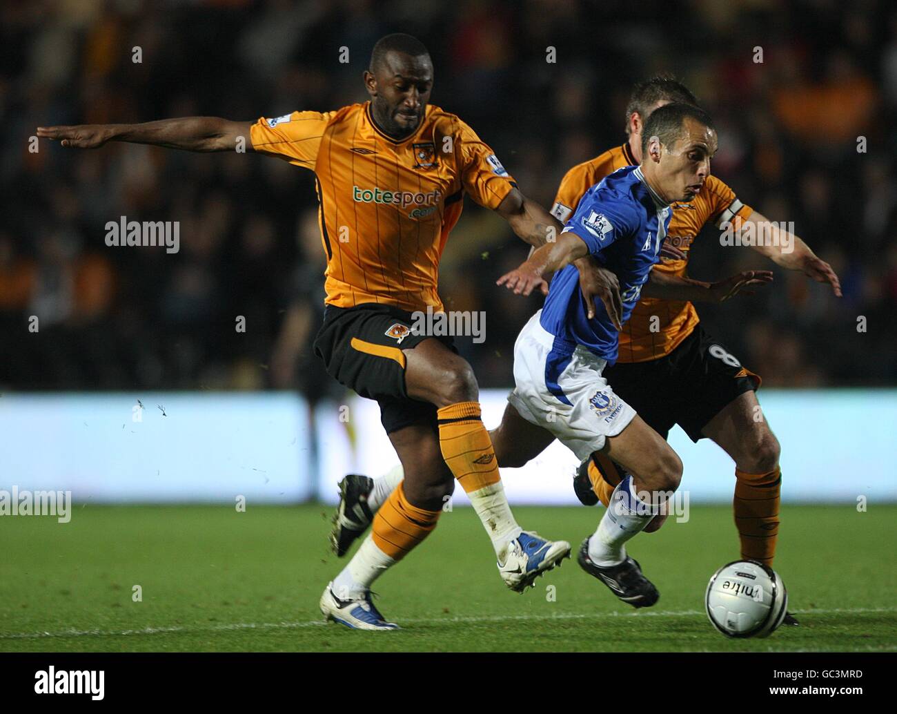 Everton's Leon Osman (centre) battles through a tackle from Hull City's ...