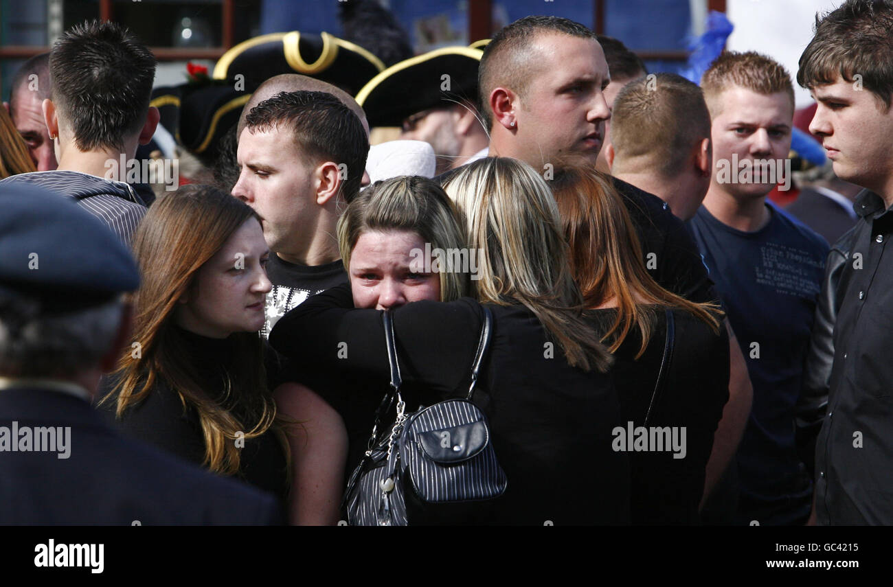Mourners comfort each other as the cortege carrying the coffin of ...