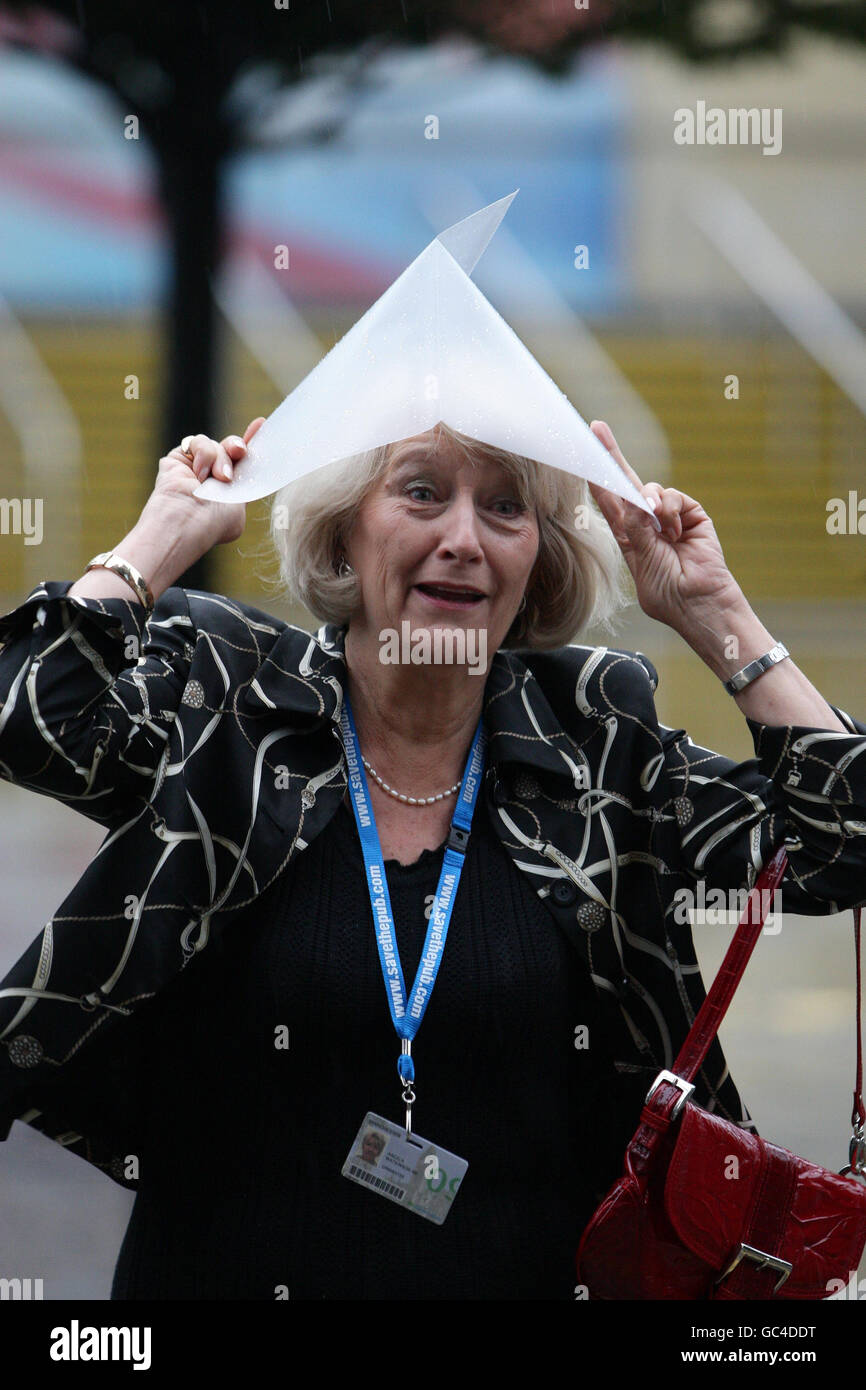 MP Angela Watkinson protects herself from the rain as she makes her way ...