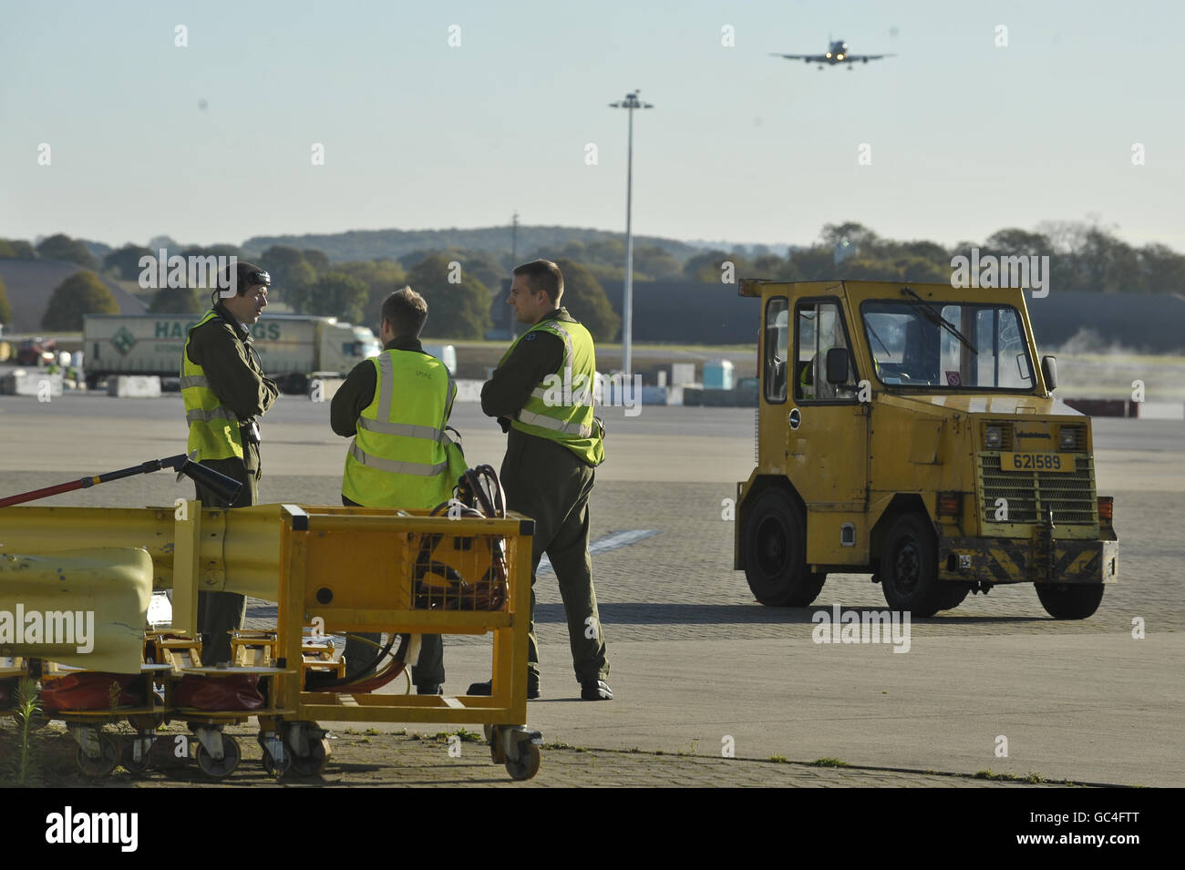 RAF ground crew stand by ground equipment as a tow truck passes by and ...