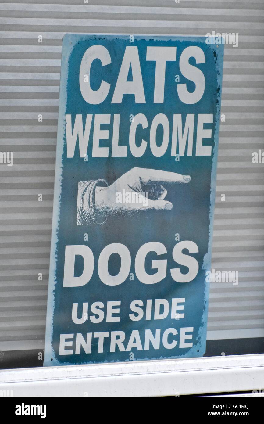 A sign displaying the words "Cats welcome, dogs use side entrance" on ...