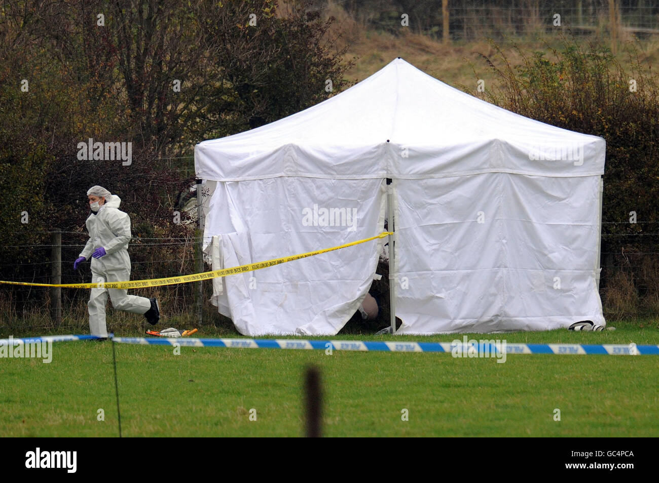 NOTE: BODY IN TENT IS VISIBLE. A forensic officer leaves a tent with ...