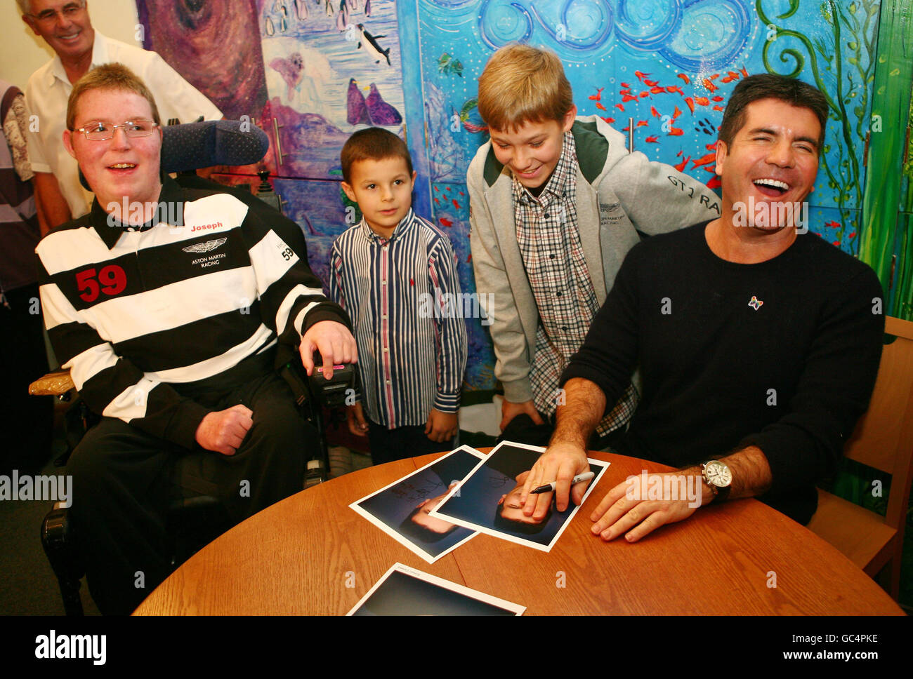 Simon Cowell signs autographs for Joseph, Alex and Mathew Ball during a ...
