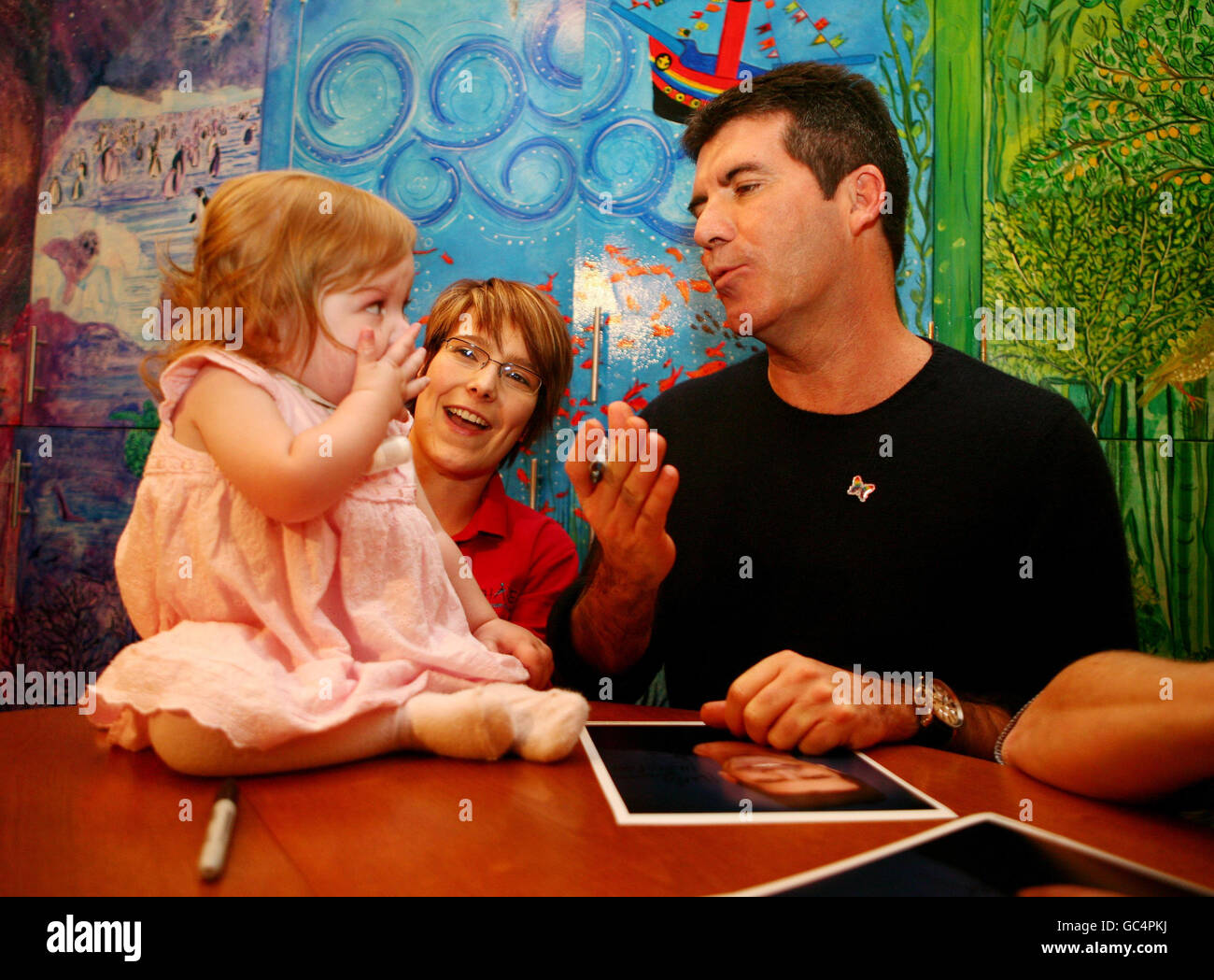 Simon Cowell signs an autograph for 19 month old Summer, during a visit ...